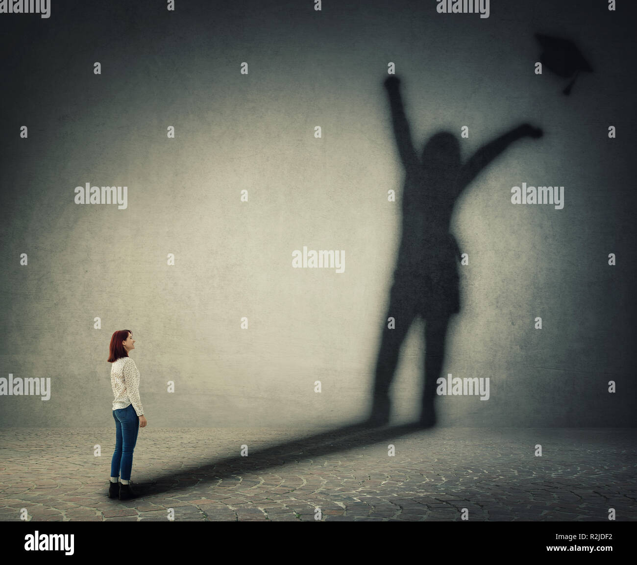 Full length female student casting a shadow on the wall celebrating ...