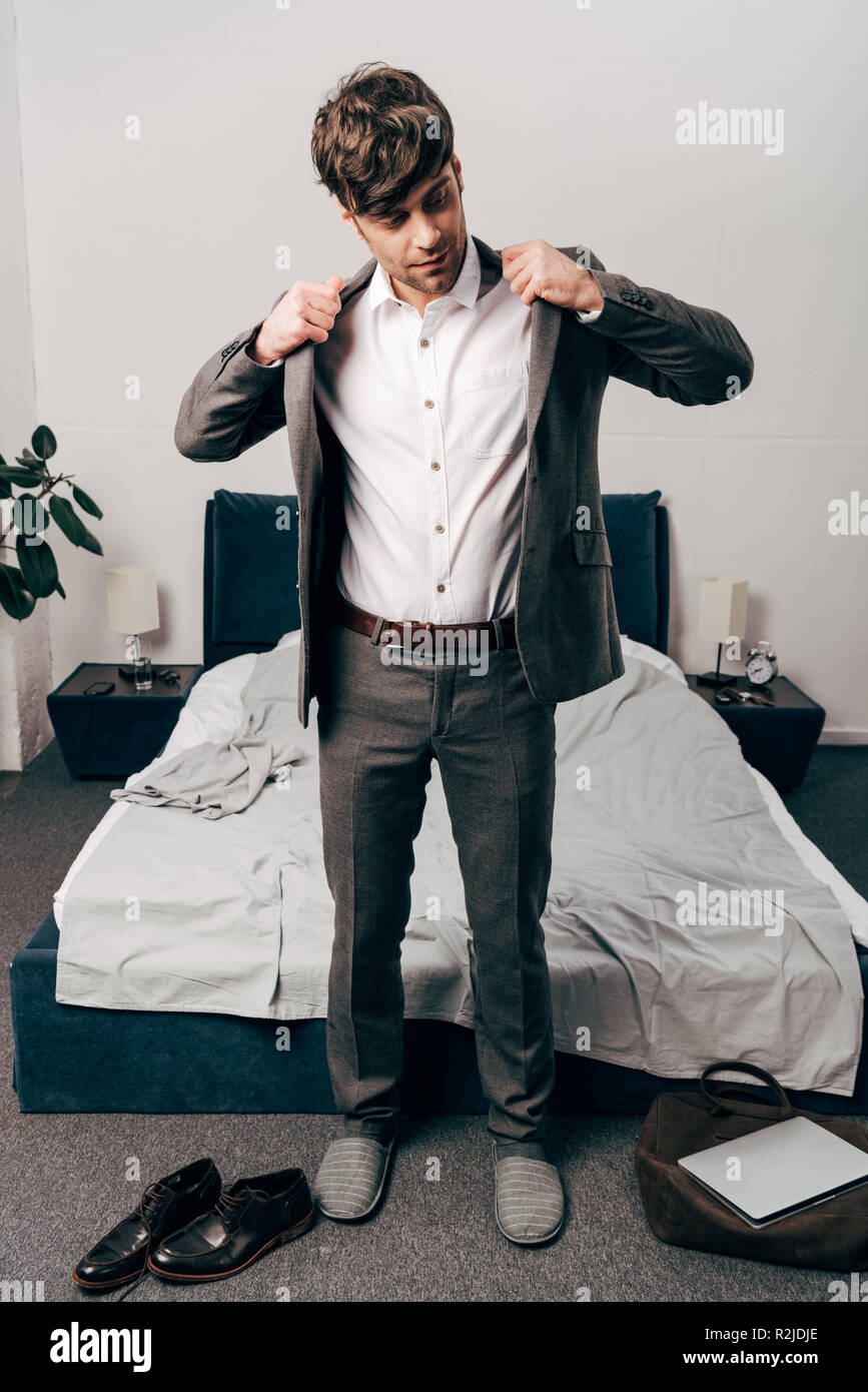 businessman putting on jacket in bedroom at home Stock Photo - Alamy