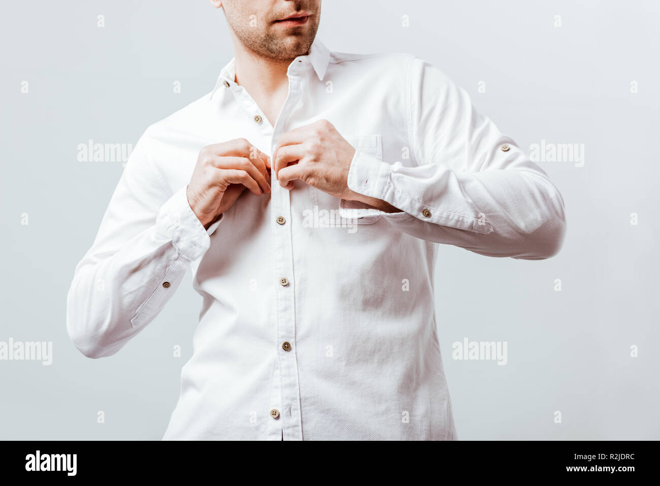 partial view of businessman buttoning up white shirt isolated on grey ...