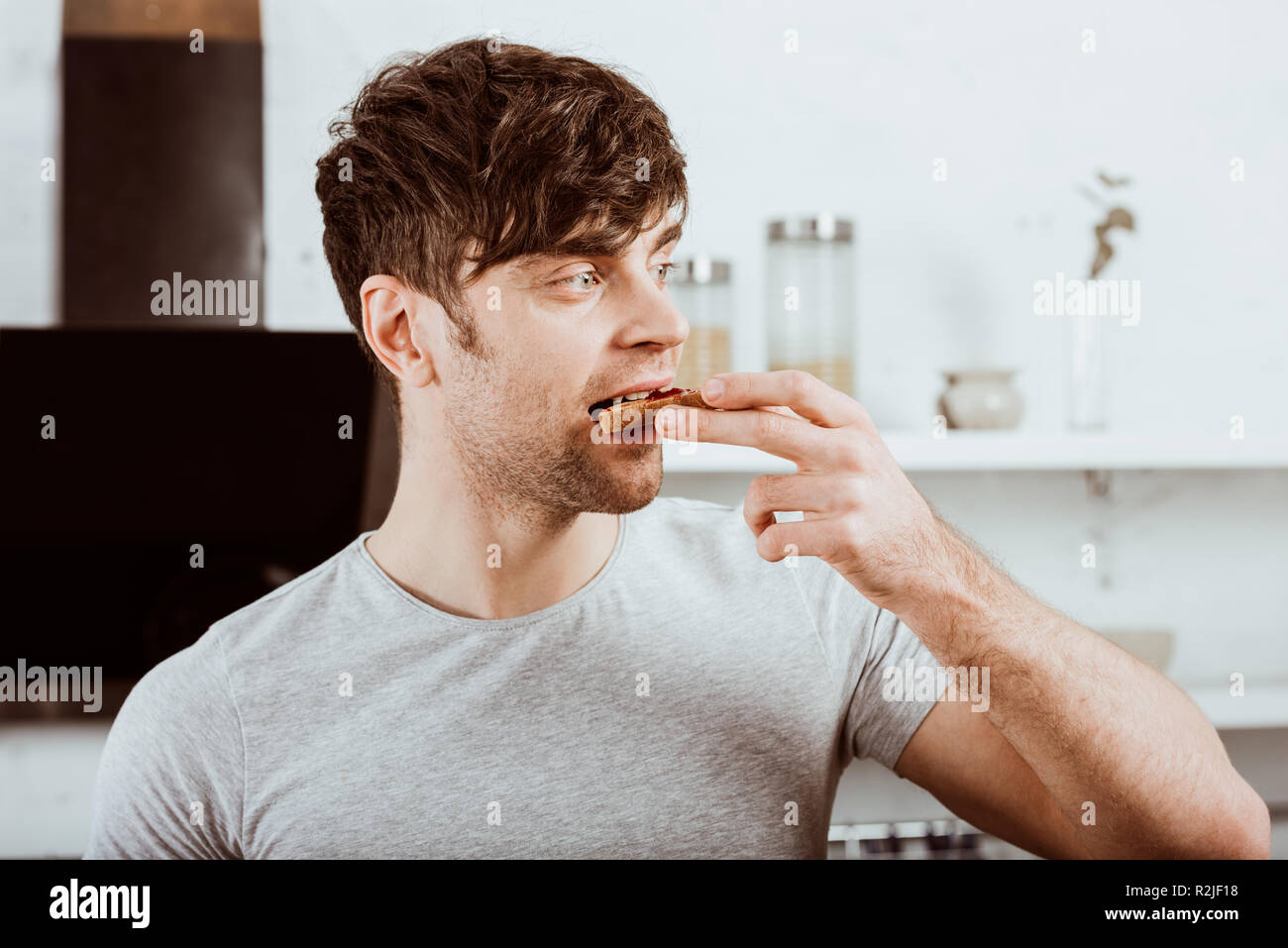 portrait of man having eating toast with jam on breakfast at kitchen ...