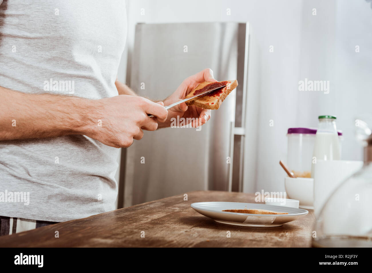 partial view of man spreading toast by jam in kitchen at home Stock ...