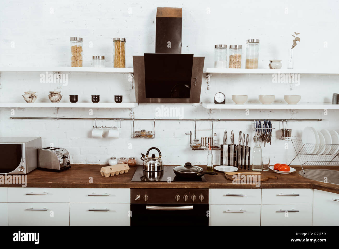 selective focus of modern kitchen interior with frying pan and teapot ...