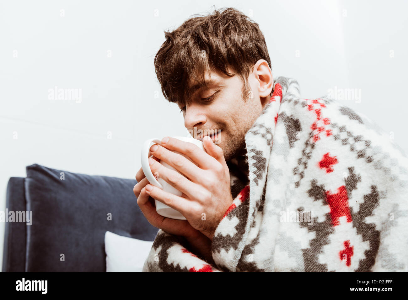 sick man wrapped in blanket drinking tea in bed at home Stock Photo - Alamy