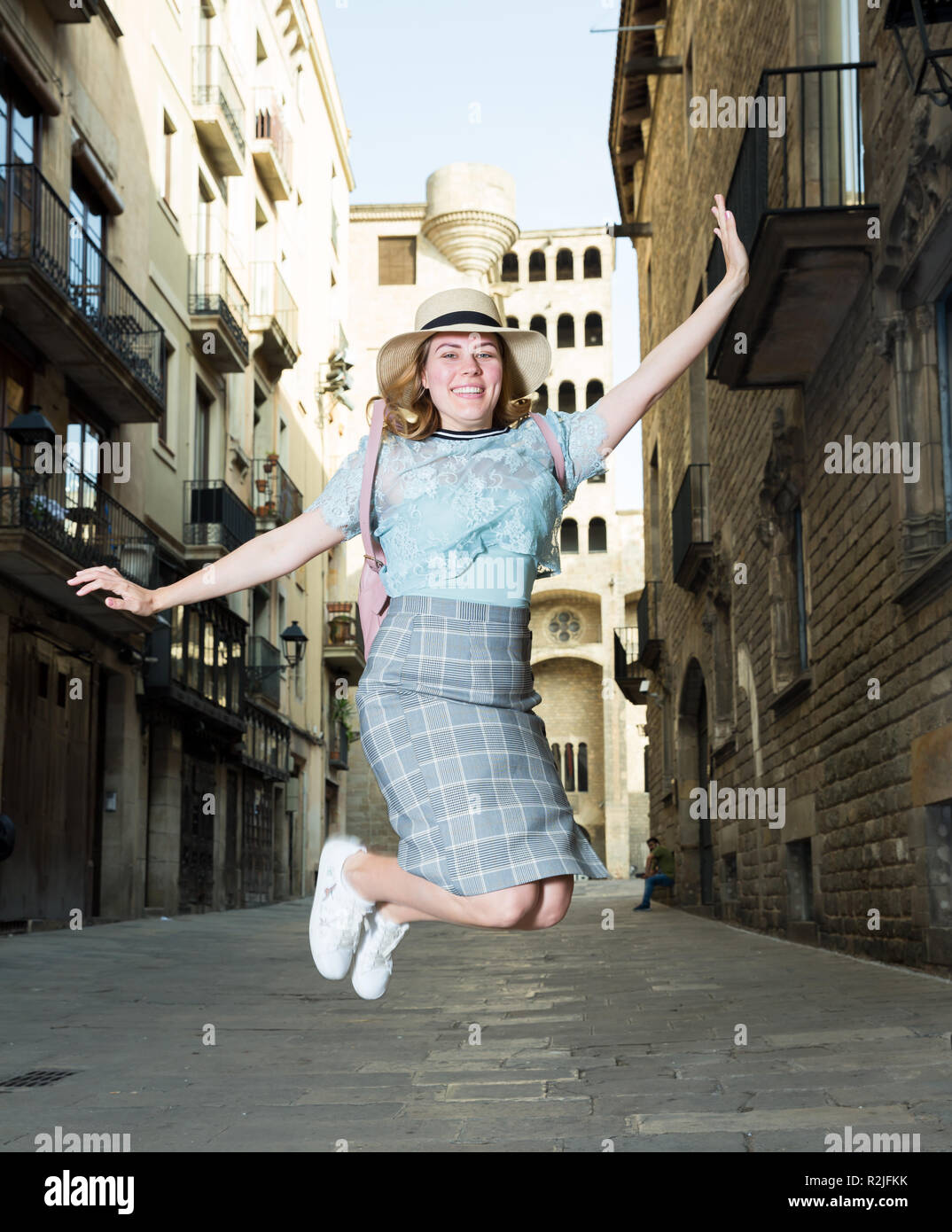 Portrait of young happy female in hat jumping in the historical city ...