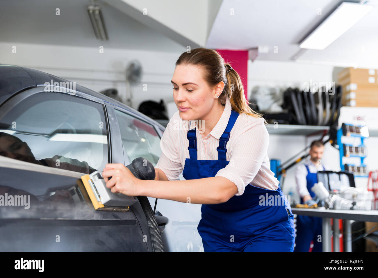 Professional female mechanic preparing automobile for painting in ...