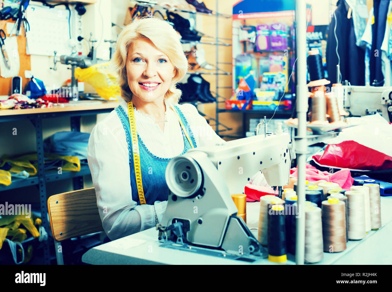 Happy mature woman tailor using sewing machine at atelier Stock Photo ...