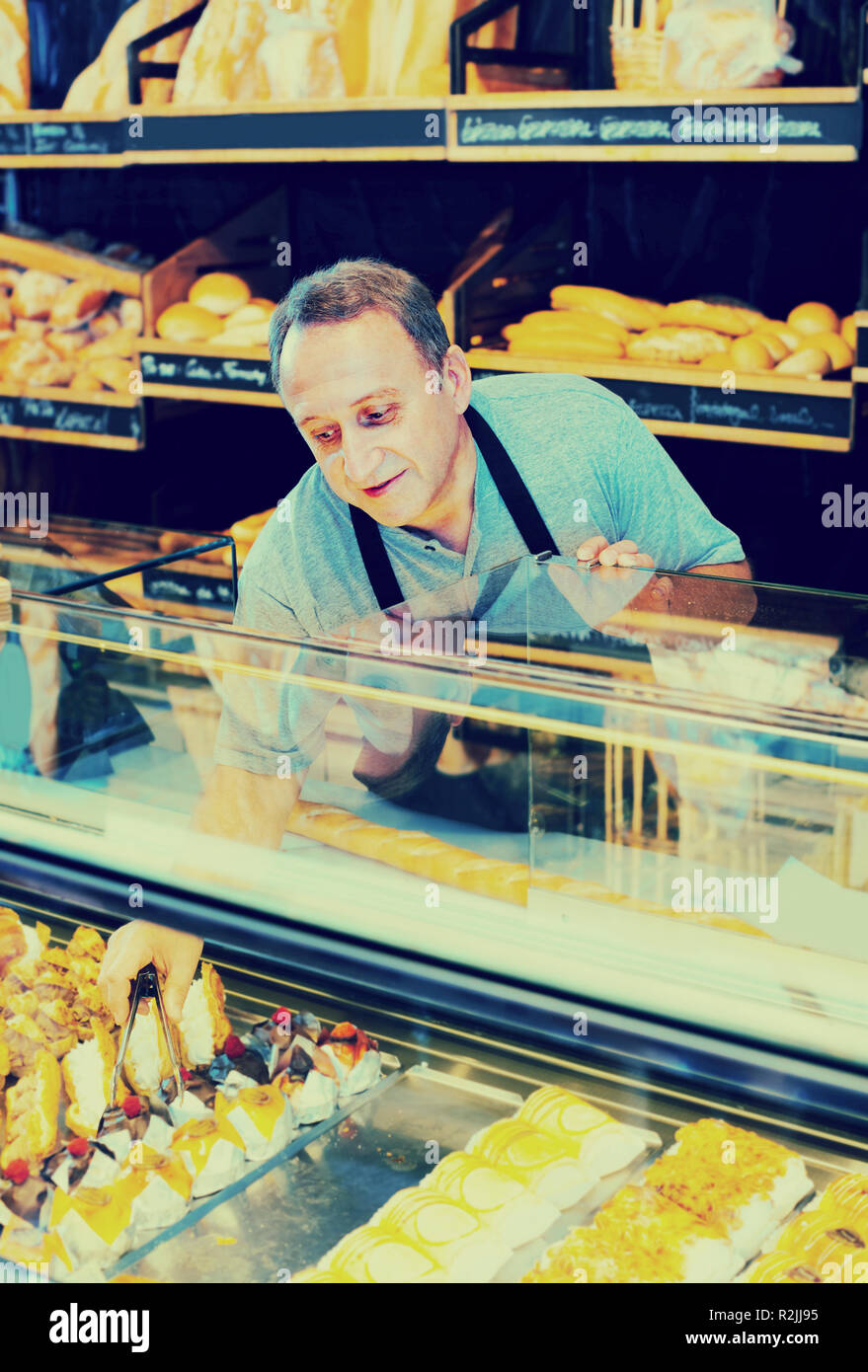 positive male staff offering fresh pastry in sweet-shop Stock Photo - Alamy