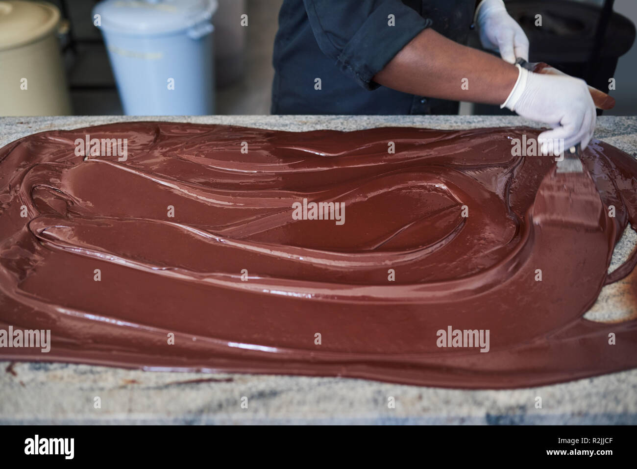 Worker spreading chocolate out with spatulas on a factory table Stock ...