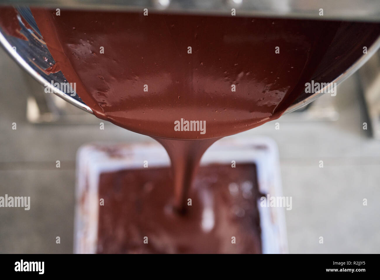 Melted chocolate pouring into a plastic container Stock Photo - Alamy