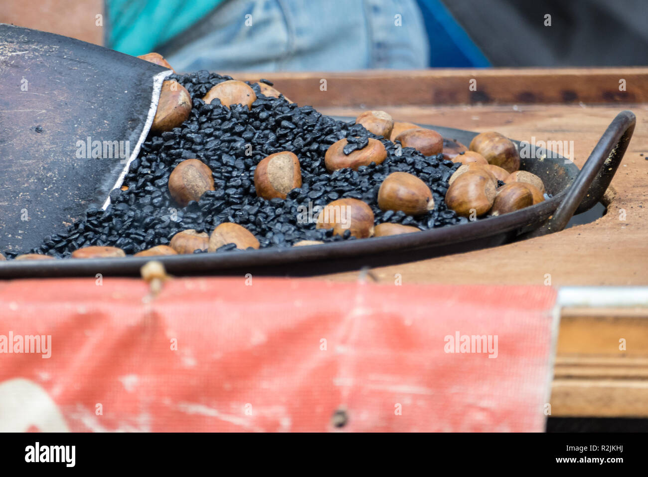 Chestnuts roasting in hot stones on vendor cart Stock Photo - Alamy