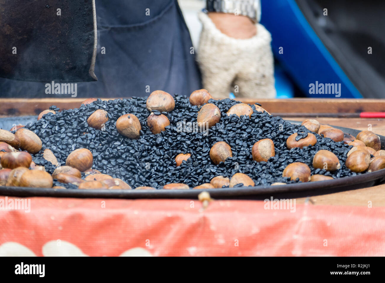 Chestnuts roasting in hot stones on vendor cart Stock Photo - Alamy