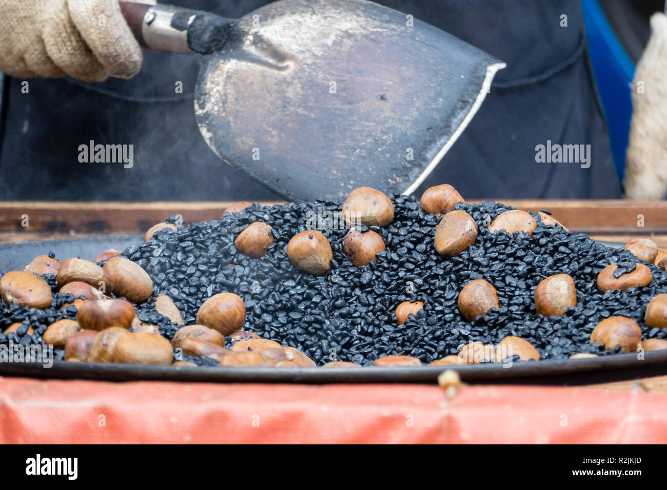 Chestnuts roasting in hot stones on vendor cart Stock Photo - Alamy