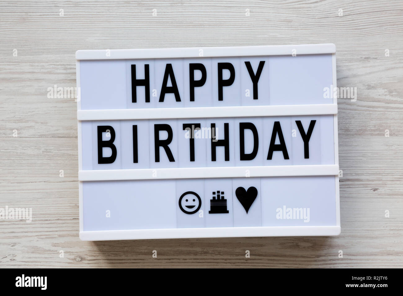 Lightbox with text 'Happy Birthday' on white wooden surface, top view. Flat lay, overhead, from ...