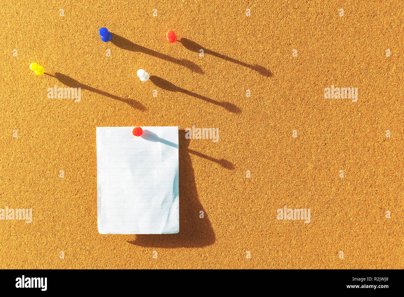 Orange Cork board with one paper note pinned and several different ...