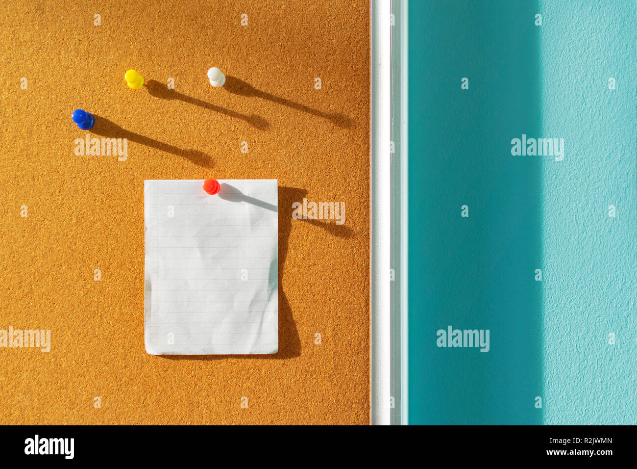 Orange Cork board with one paper note pinned and several different ...