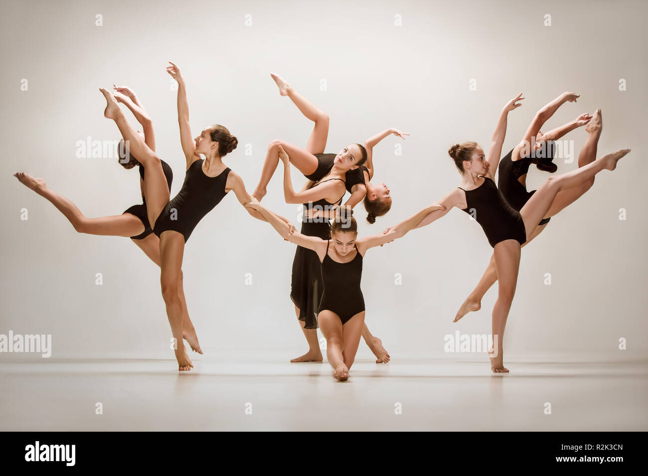 The group of modern ballet dancers dancing on gray studio background ...