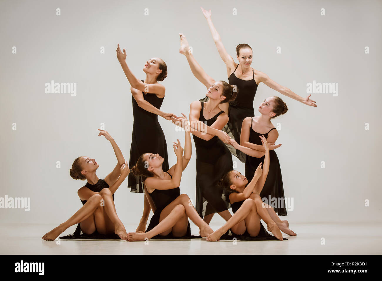 The group of modern ballet dancers dancing on gray studio background ...