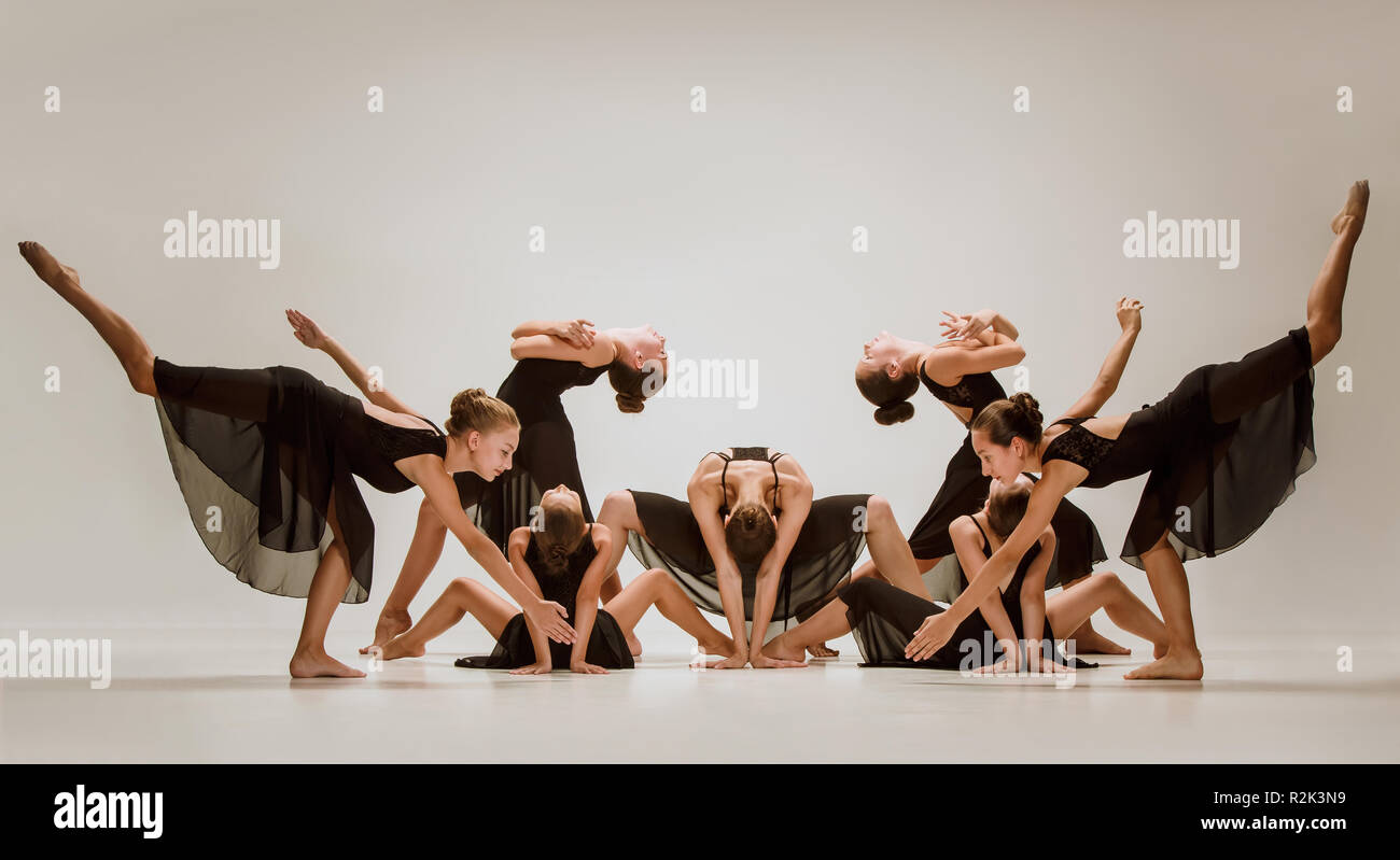 The group of modern ballet dancers dancing on gray studio background ...
