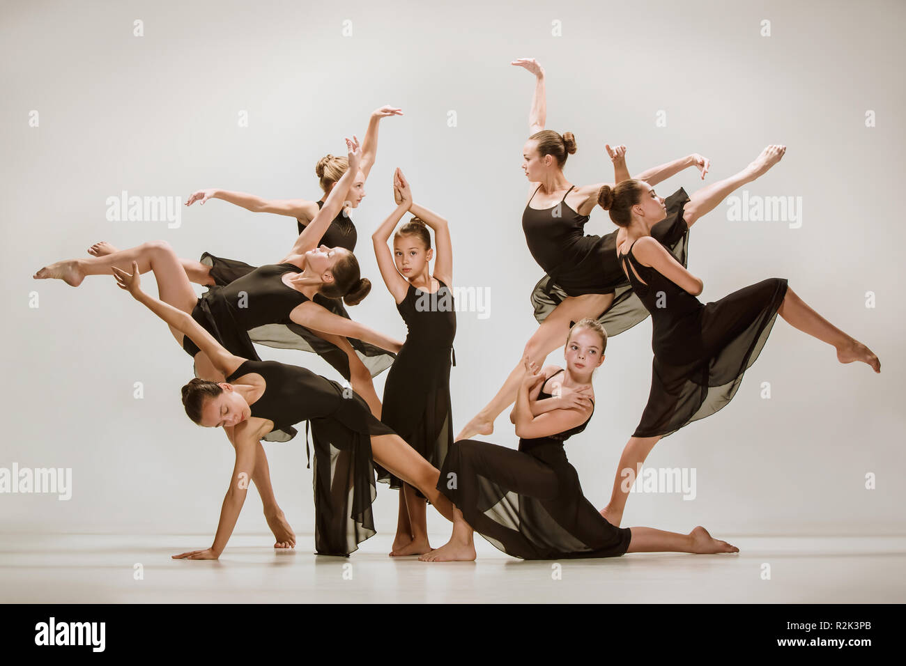 The group of modern ballet dancers dancing on gray studio background ...