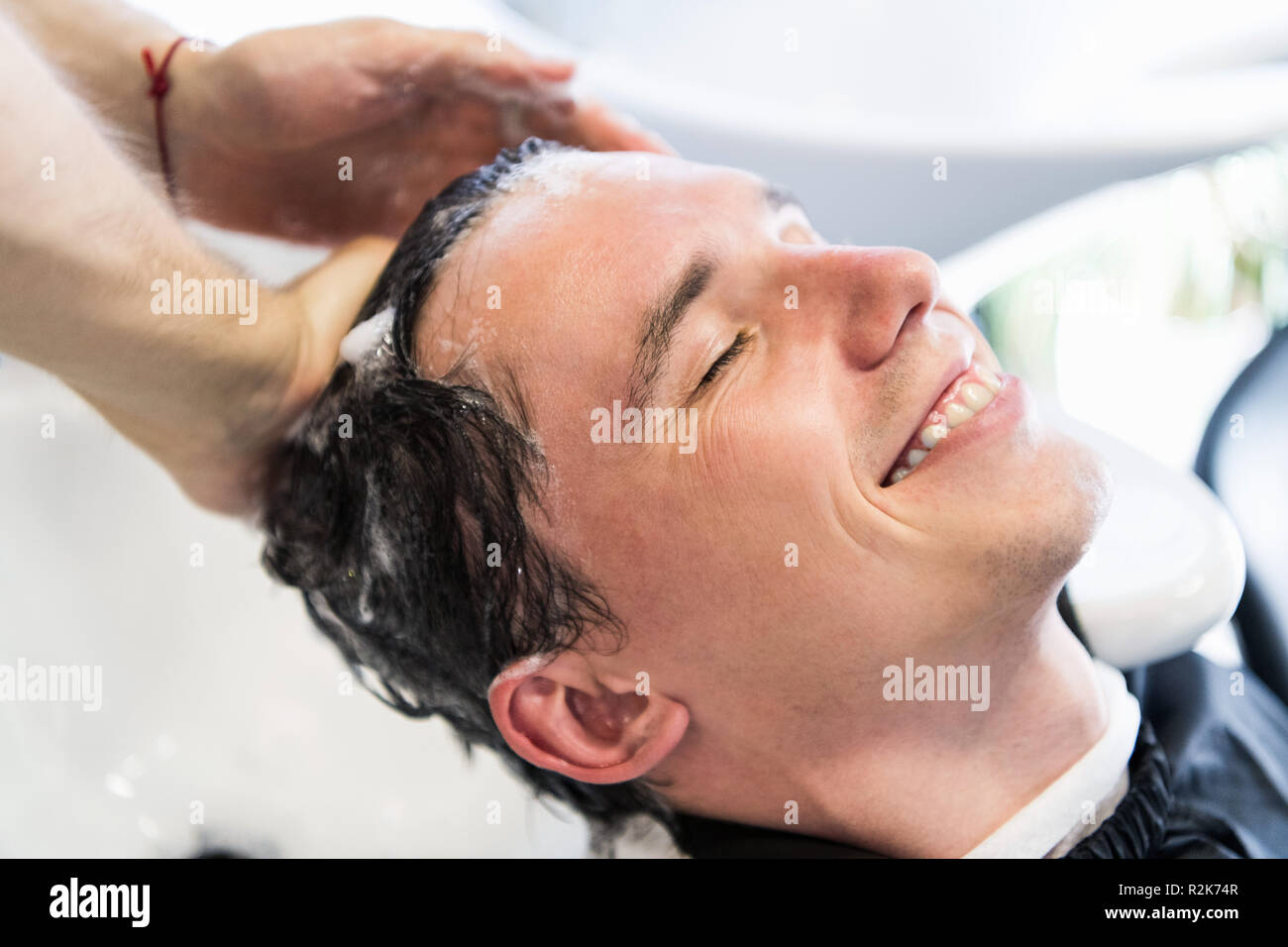 Close-up of a young caucasian man having his hair washed in a ...