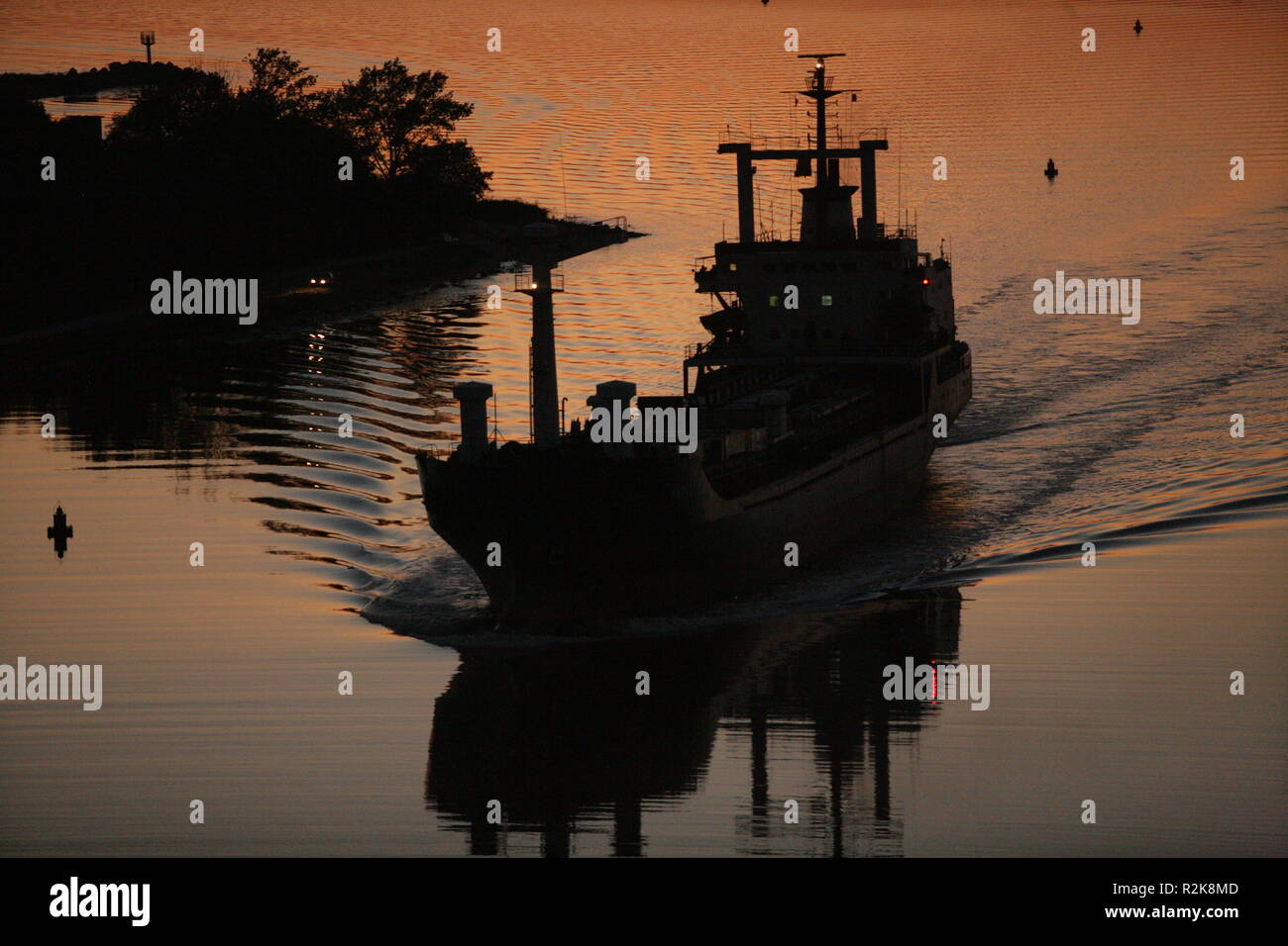 A small ship crousing during a sunset Stock Photo - Alamy