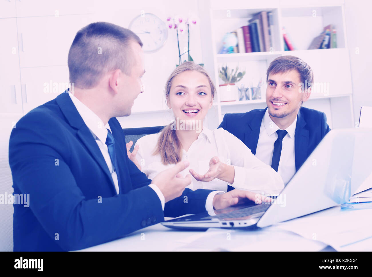 Three young business male and female assistants in formalwear having a ...
