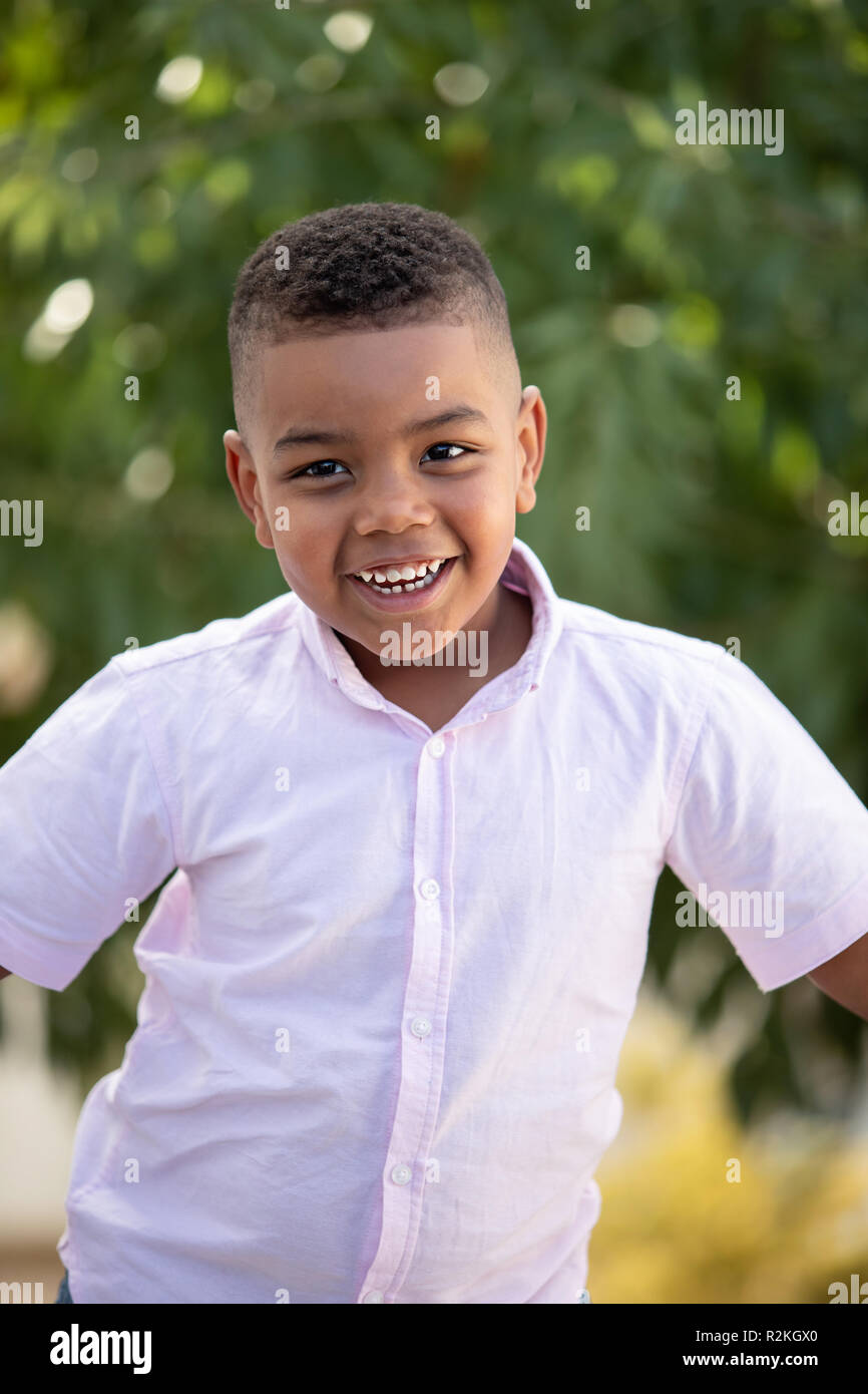Adorable latin child in the garden with a beautiful green of background ...