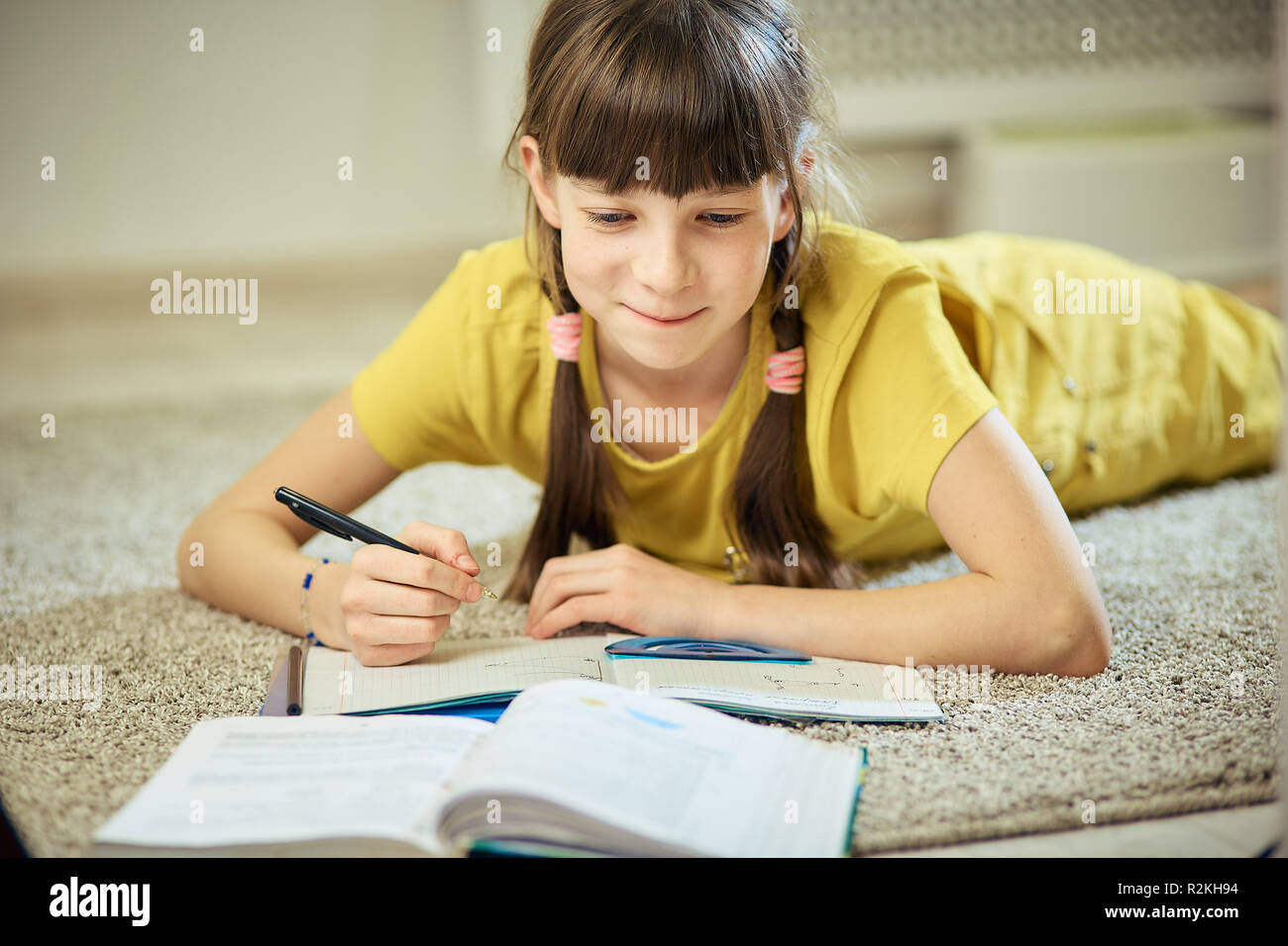teen girl doing homework sitting on the carpet in her room Stock Photo ...