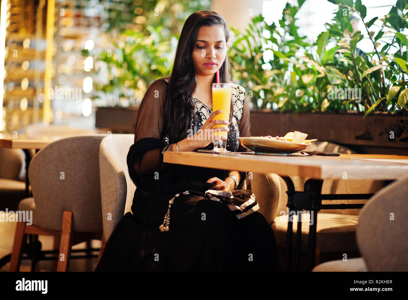 Pretty indian girl in black saree dress posed at restaurant, sitting at ...