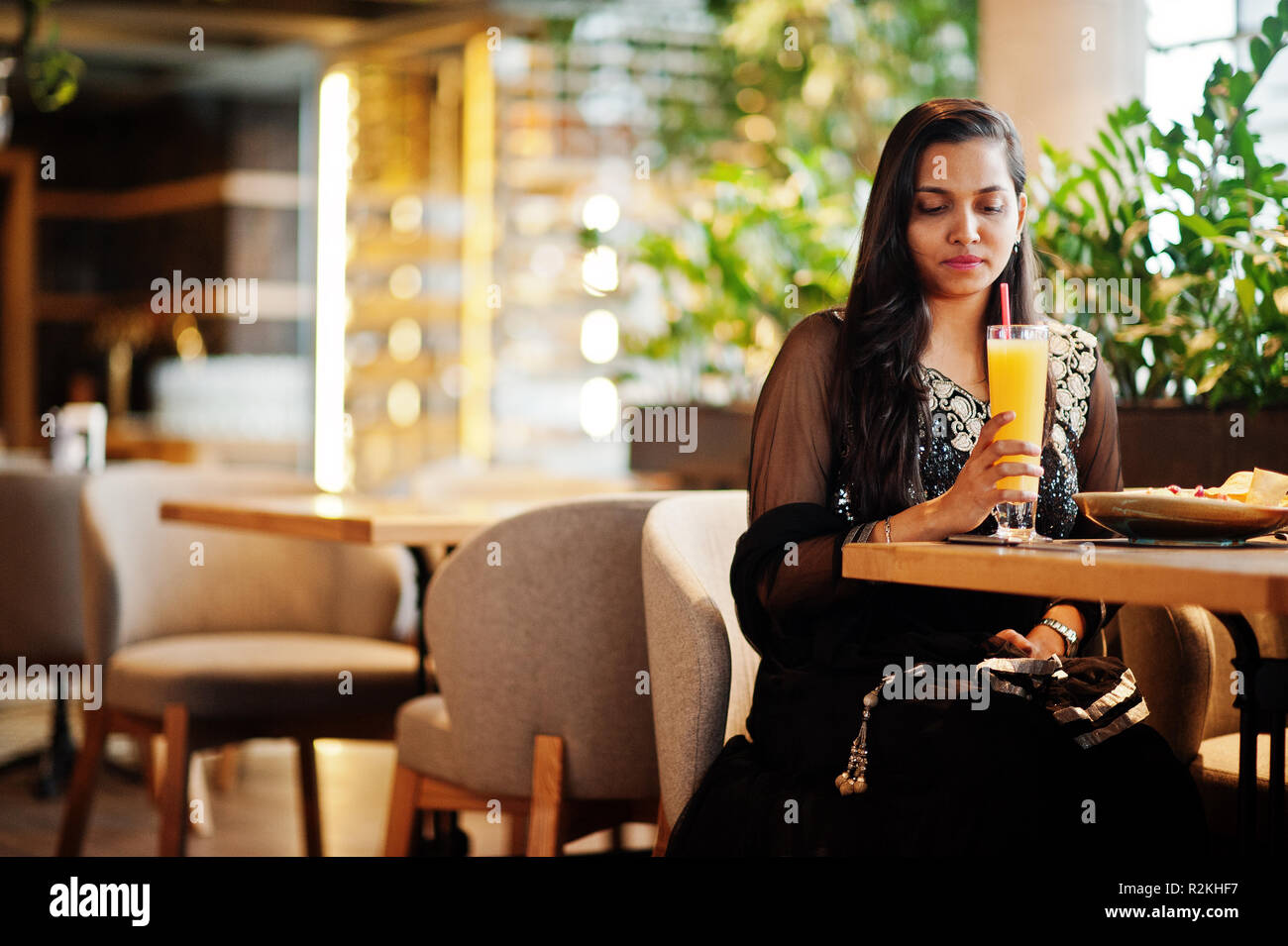 Pretty indian girl in black saree dress posed at restaurant, sitting at ...