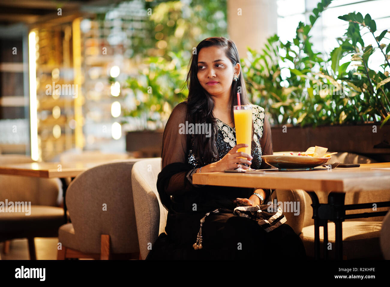 Pretty indian girl in black saree dress posed at restaurant, sitting at ...