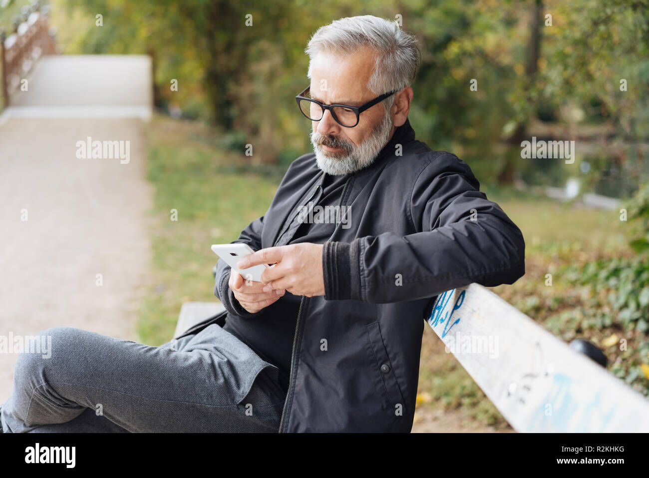 Attractive Mature Bearded Man Wearing Glasses Relaxing On A Park Bench