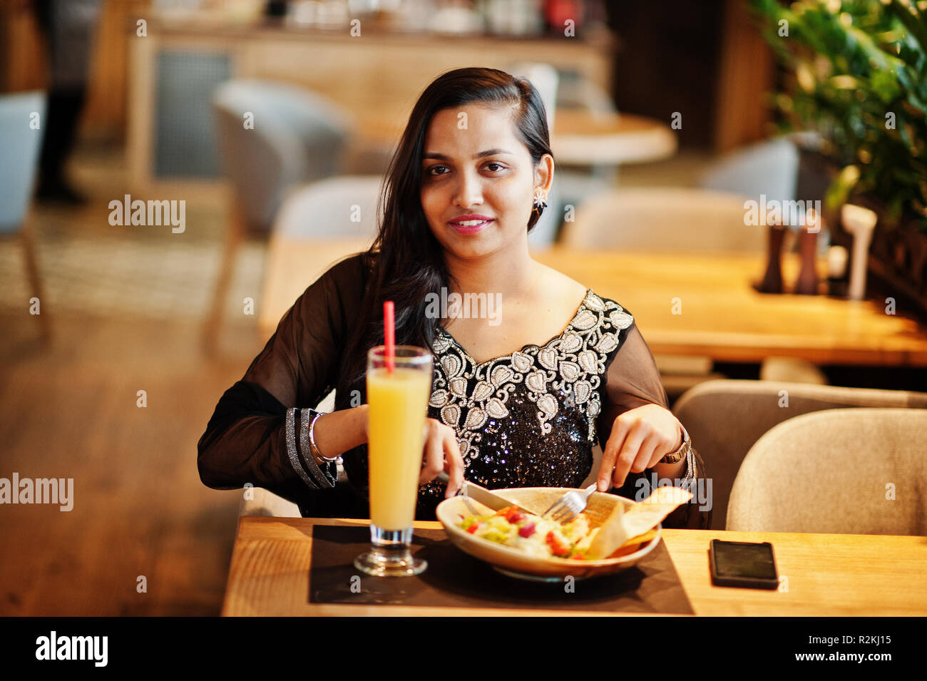 Pretty indian girl in black saree dress posed at restaurant, sitting at ...