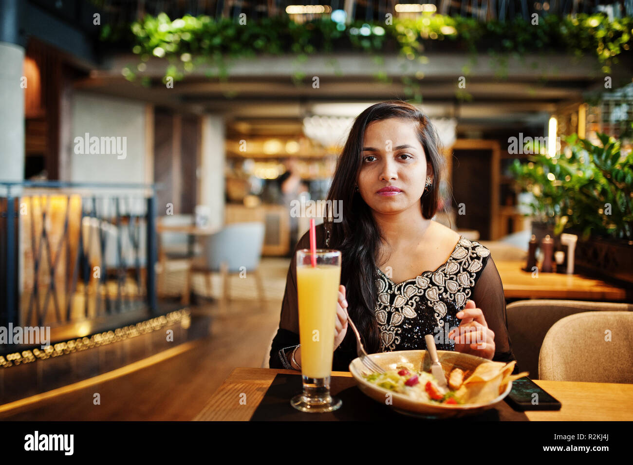 Pretty indian girl in black saree dress posed at restaurant, sitting at ...