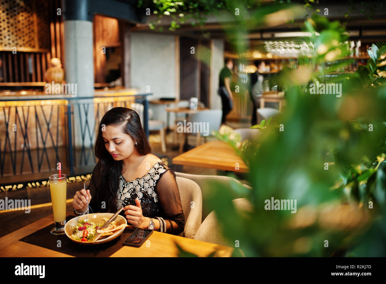 Pretty indian girl in black saree dress posed at restaurant, sitting at ...