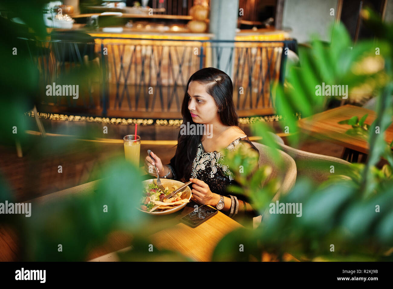 Pretty indian girl in black saree dress posed at restaurant, sitting at ...