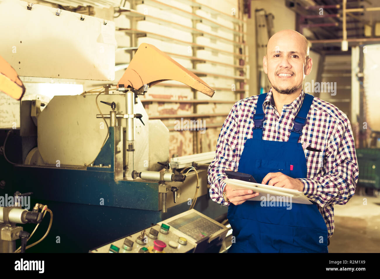 Positive labour in uniform working on lathe machine at factory Stock ...