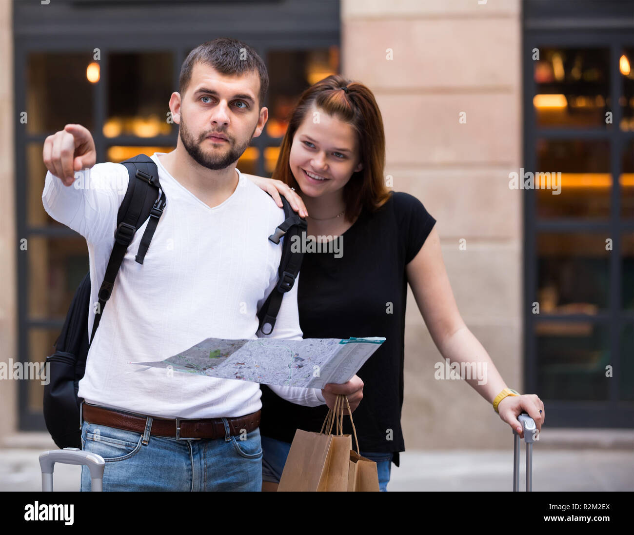 Portrait of two smiling tourists with map walking with baggage on ...