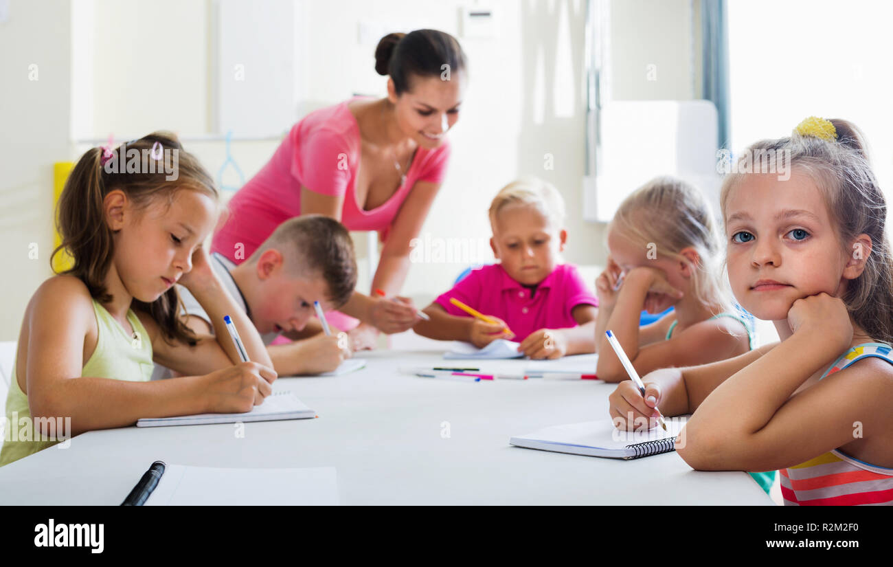 Glad cheerful diligent kids learning to write on lesson in elementary ...