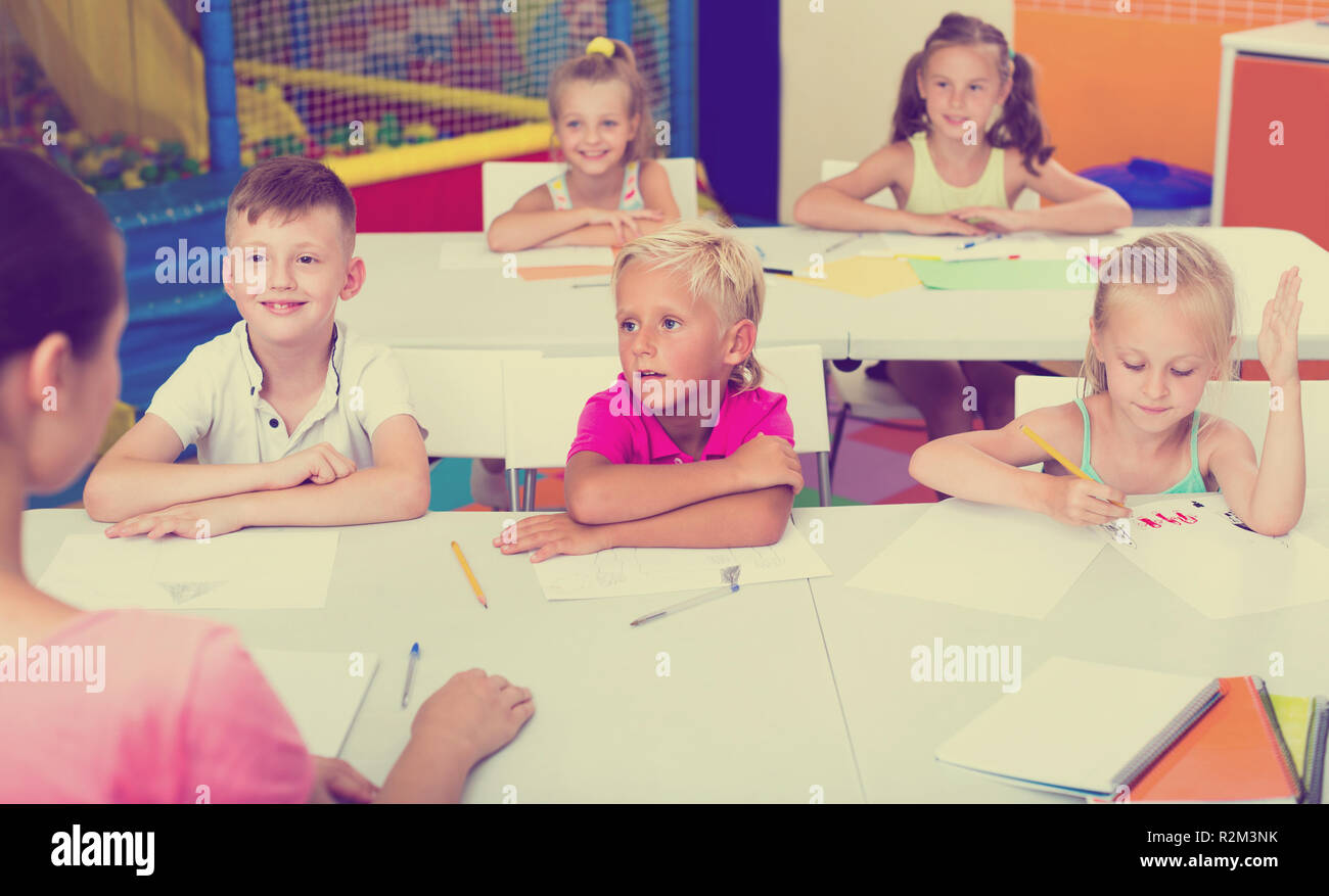 Attentive kids sitting and listening cheerful teacher in elementary ...