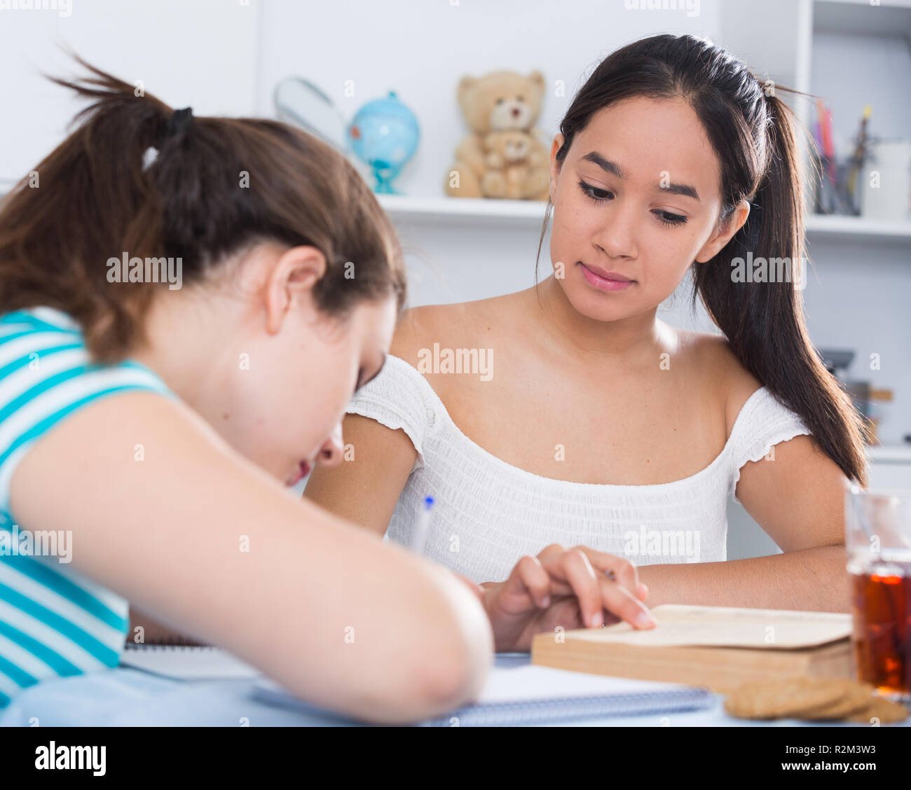 Teens girls studying together at home, doing homework and discussing ...
