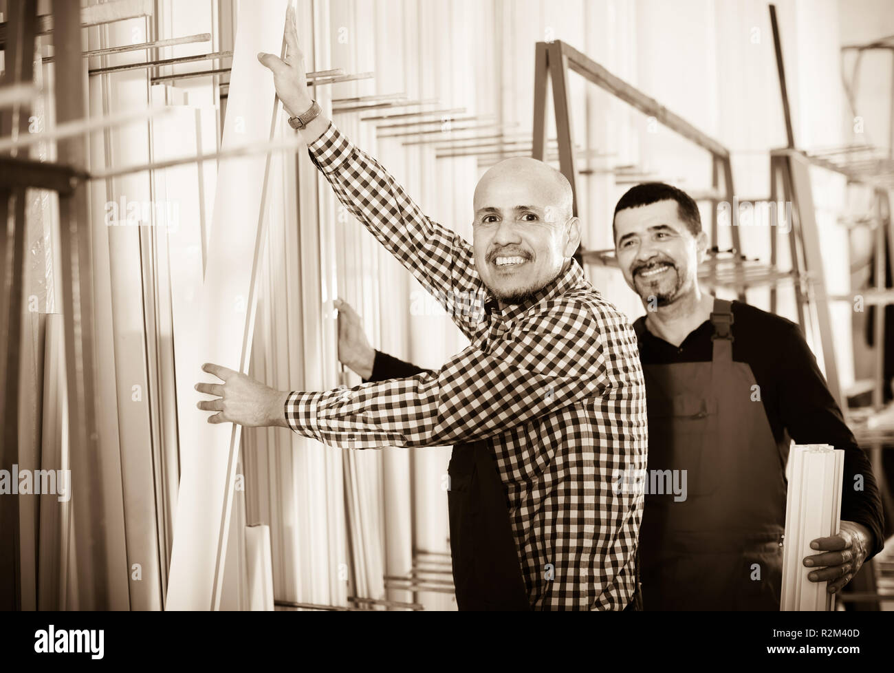 Two careful men in uniform inspecting PVC manufacturing output in ...