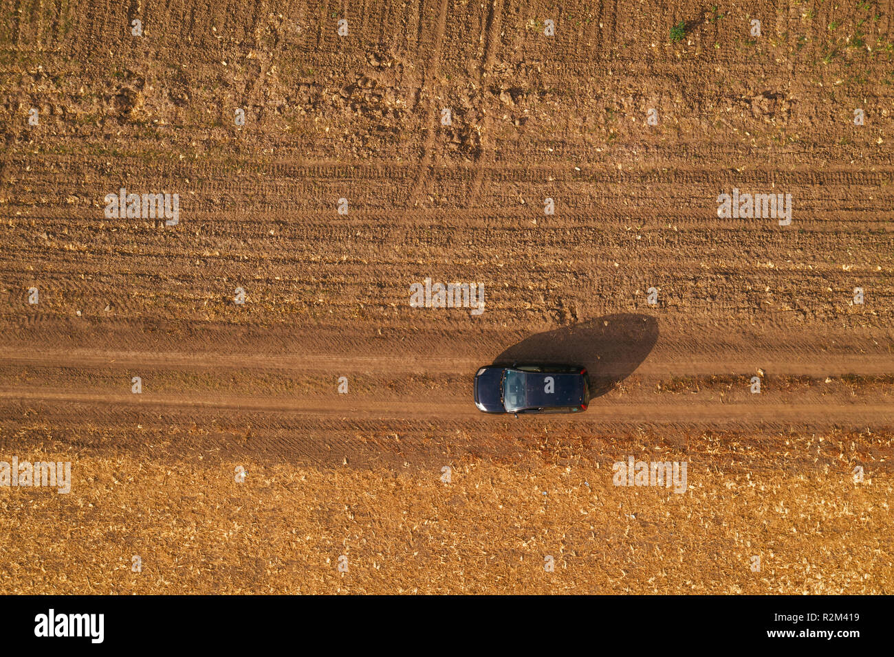 Aerial view of black car on dirt road through countryside, top view of ...