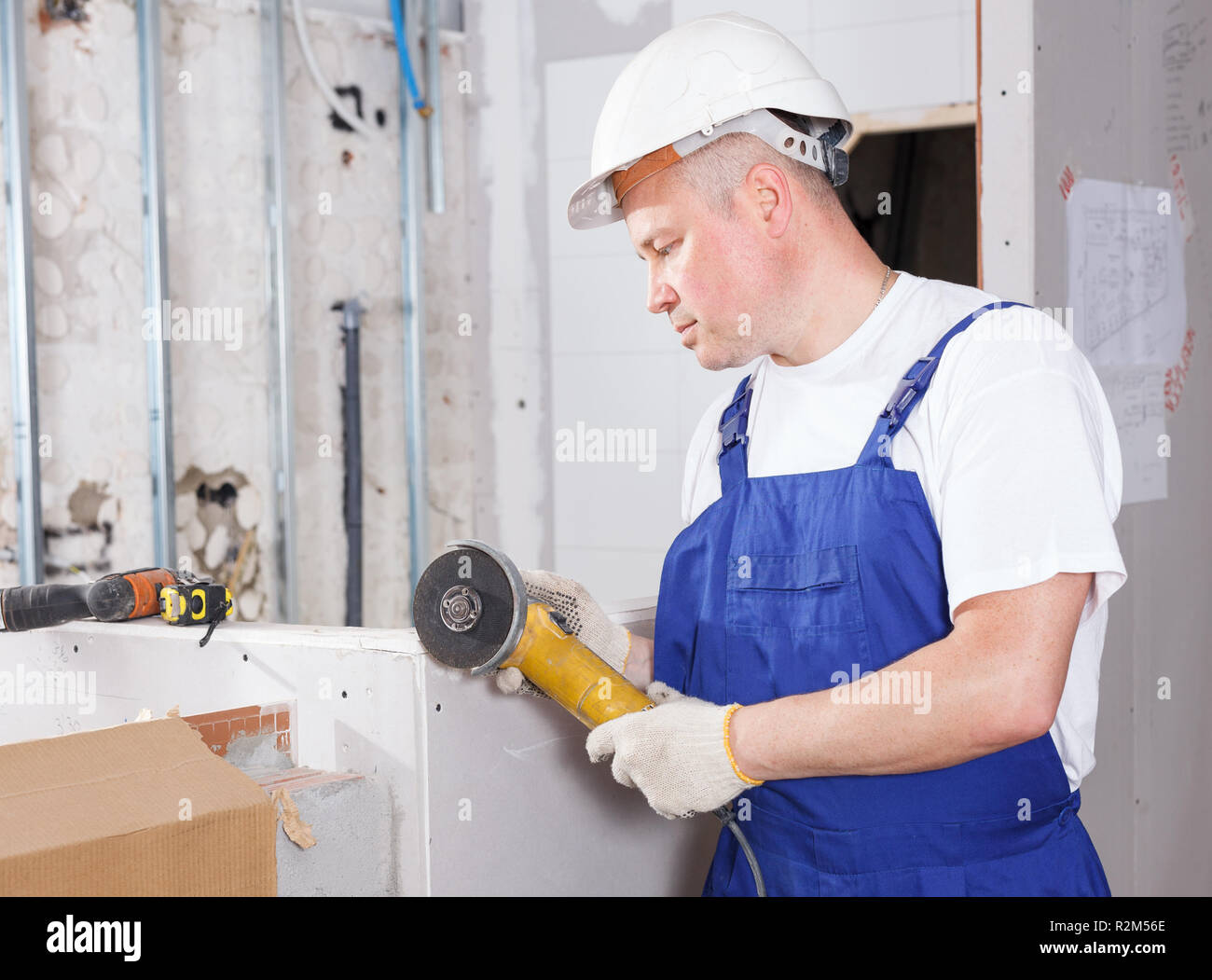 Construction worker using handheld circular saw at indoors building ...