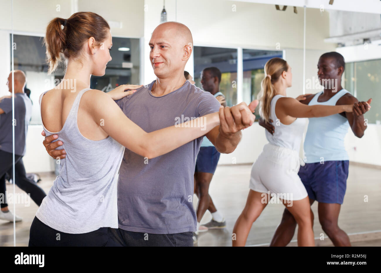 Young smiling people exercising waltz movements in pairs at the dancing ...