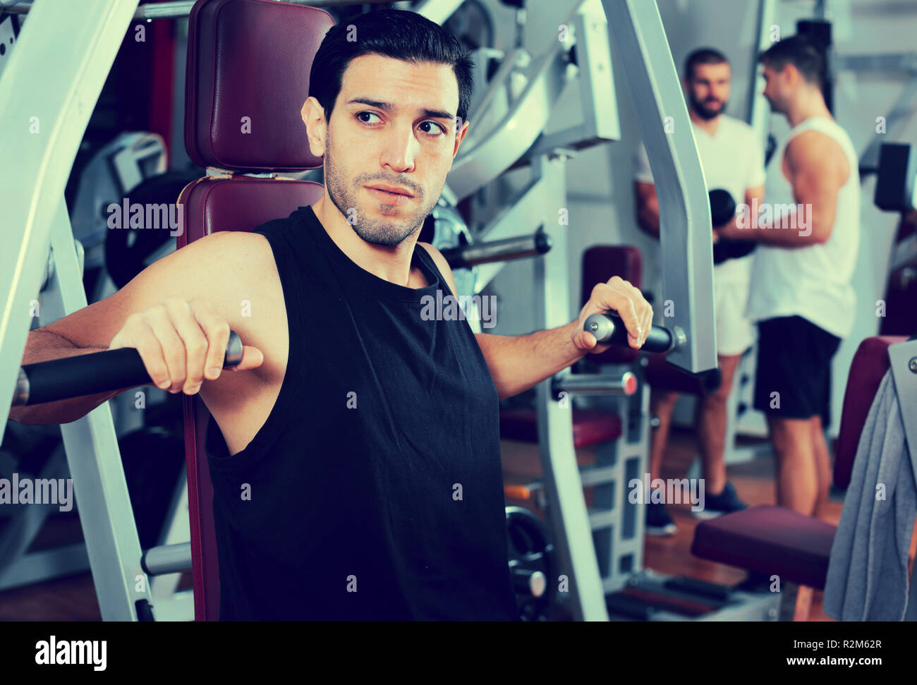 Portrait of athletic man during workout with power exercise machine in ...