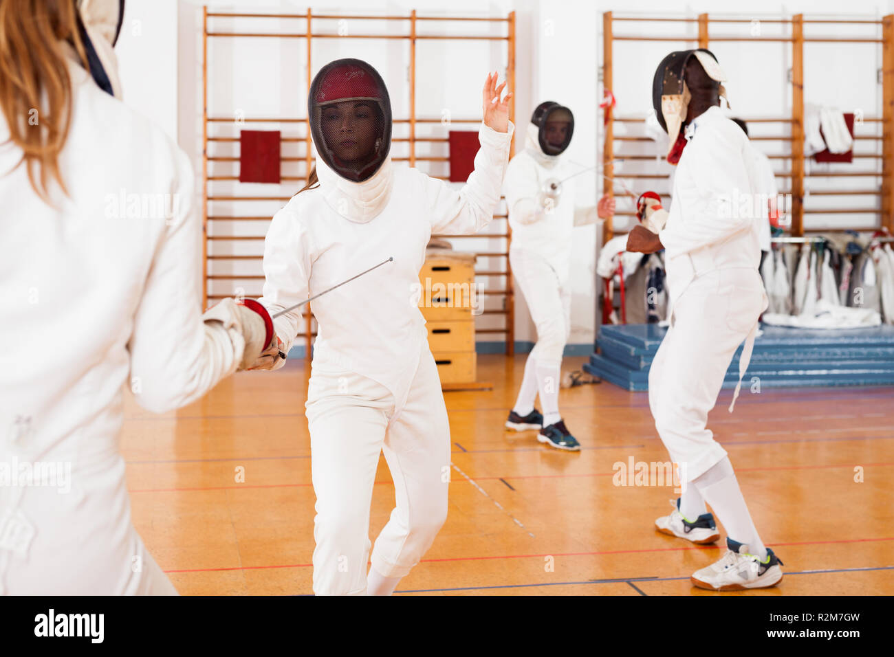 Two glad cheerful positive female fencers exercising movements in duel ...