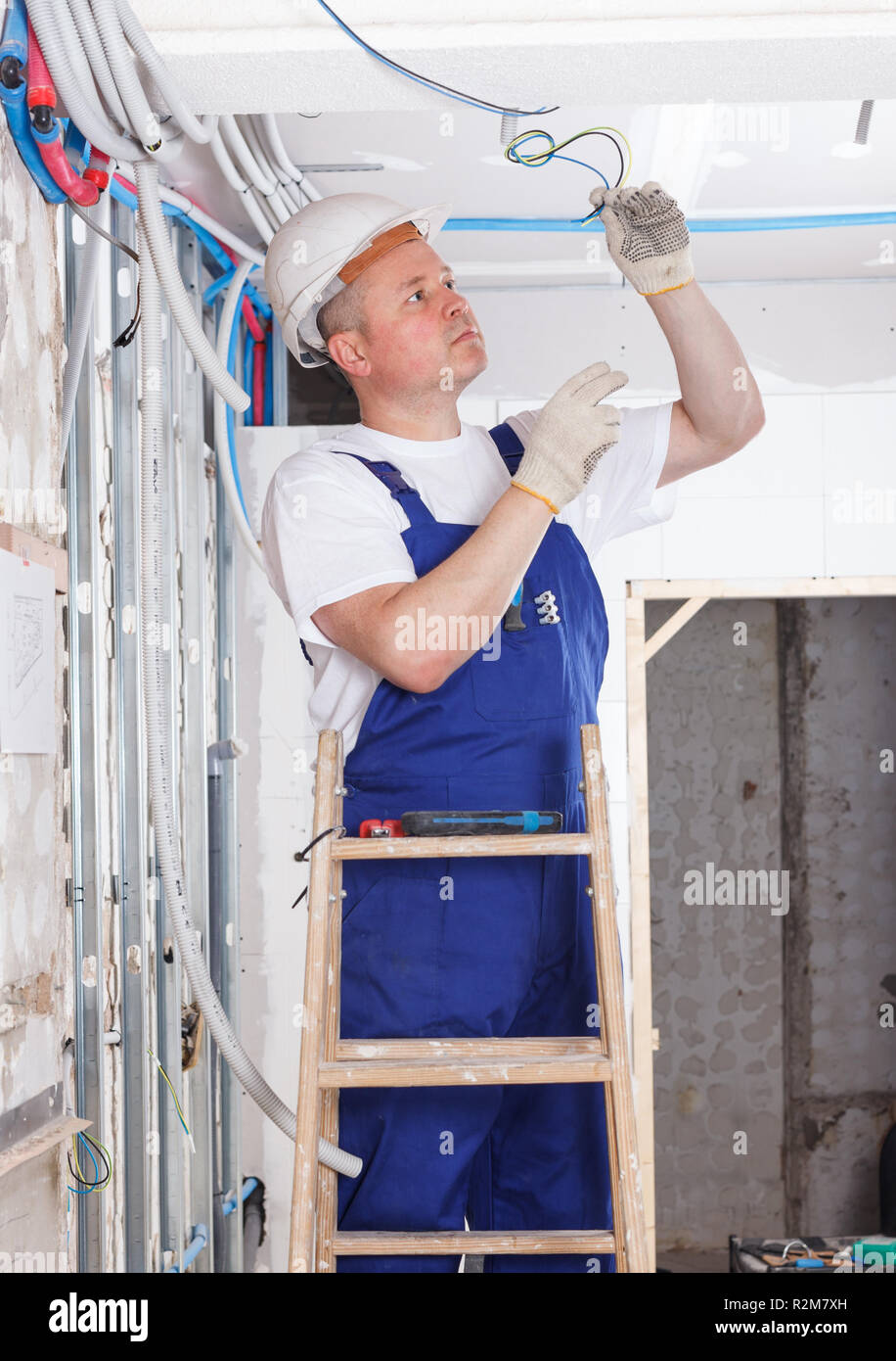 Professional builder engaged in electrical installation work at indoors ...
