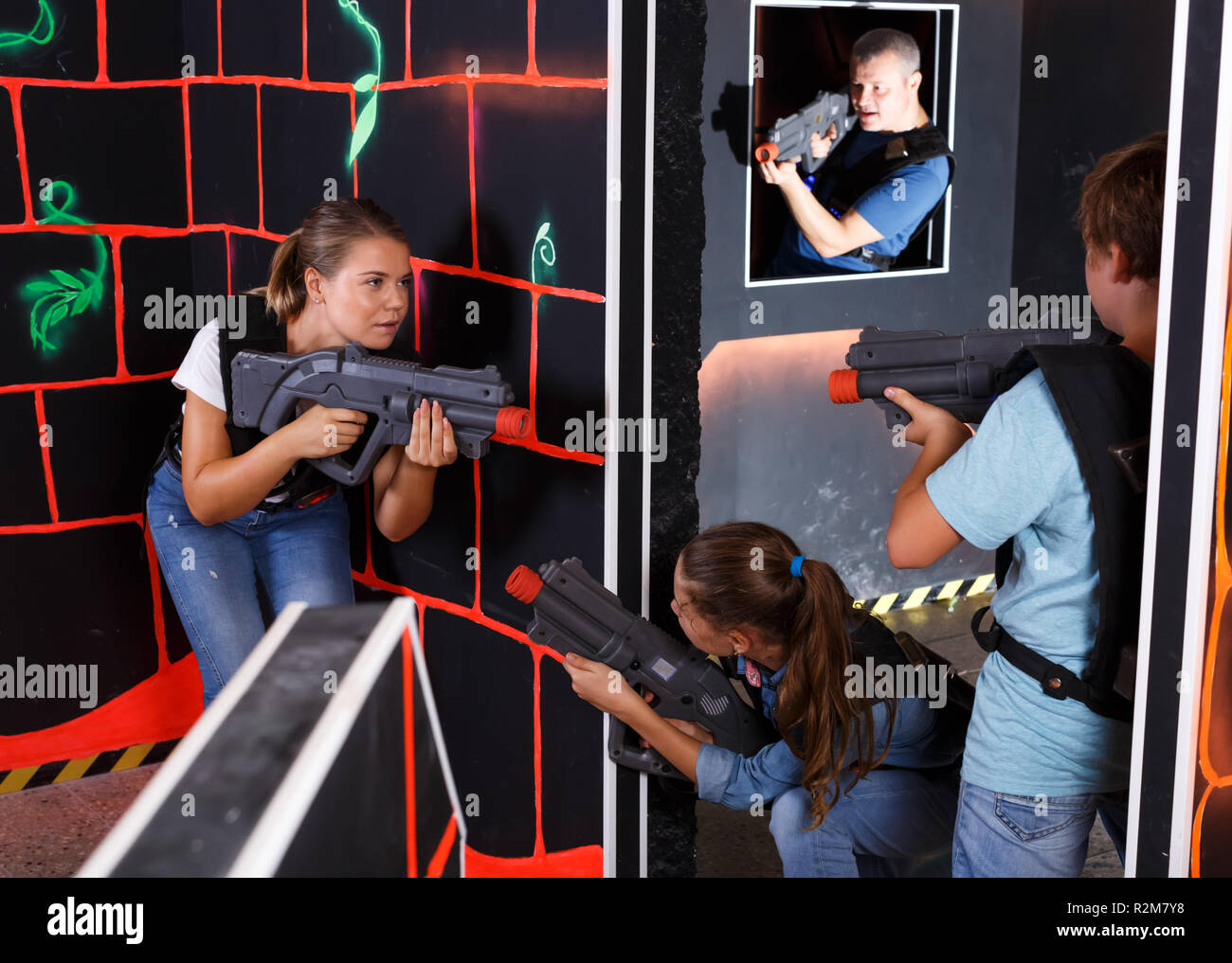 Group of positive kids and adults with laser guns having fun on ...