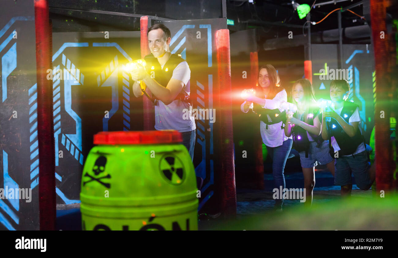 Group of happy kids and adults having fun on dark lasertag arena in ...